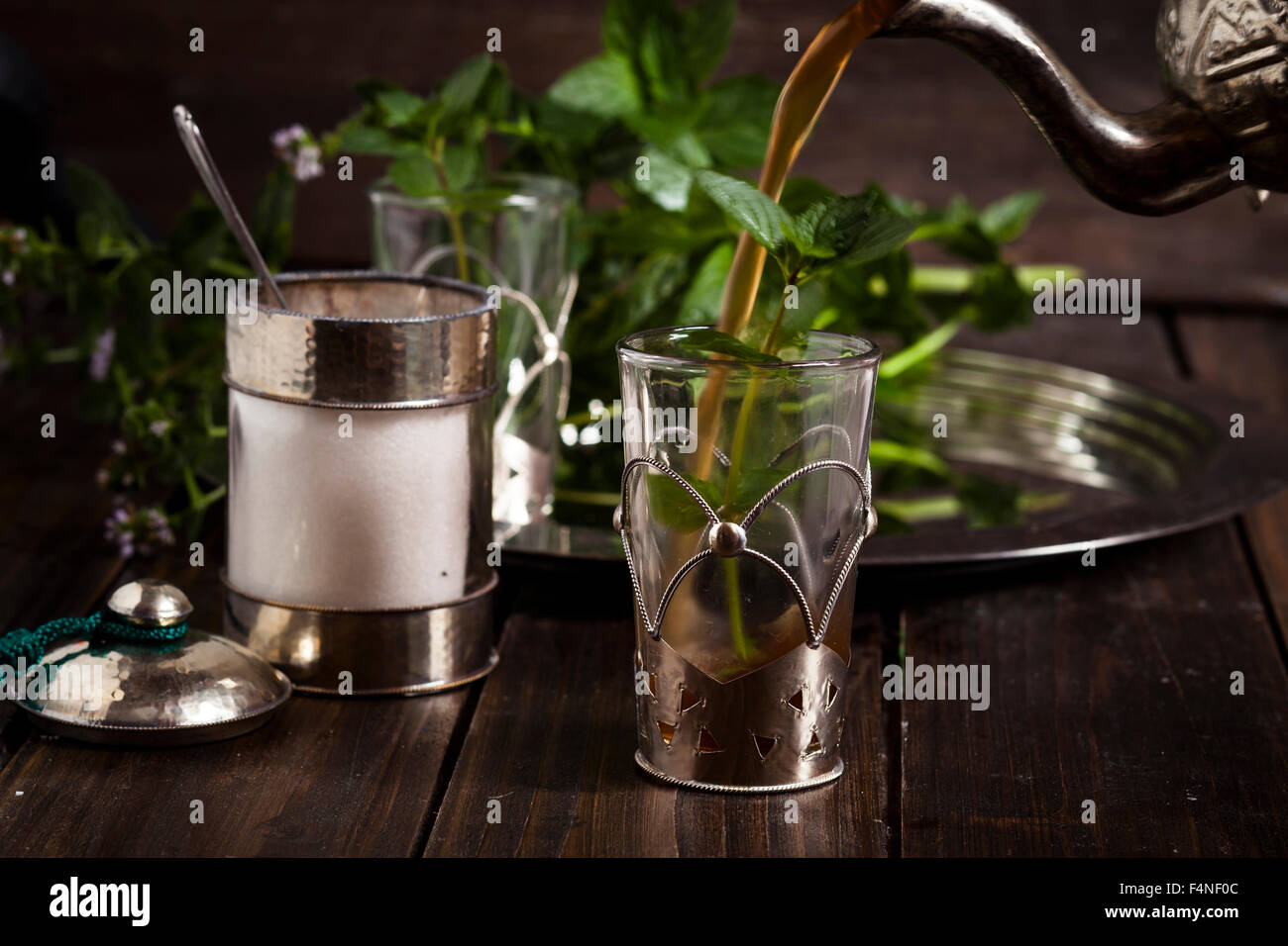 Pouring black tea into traditional North African tea glass with fresh ...