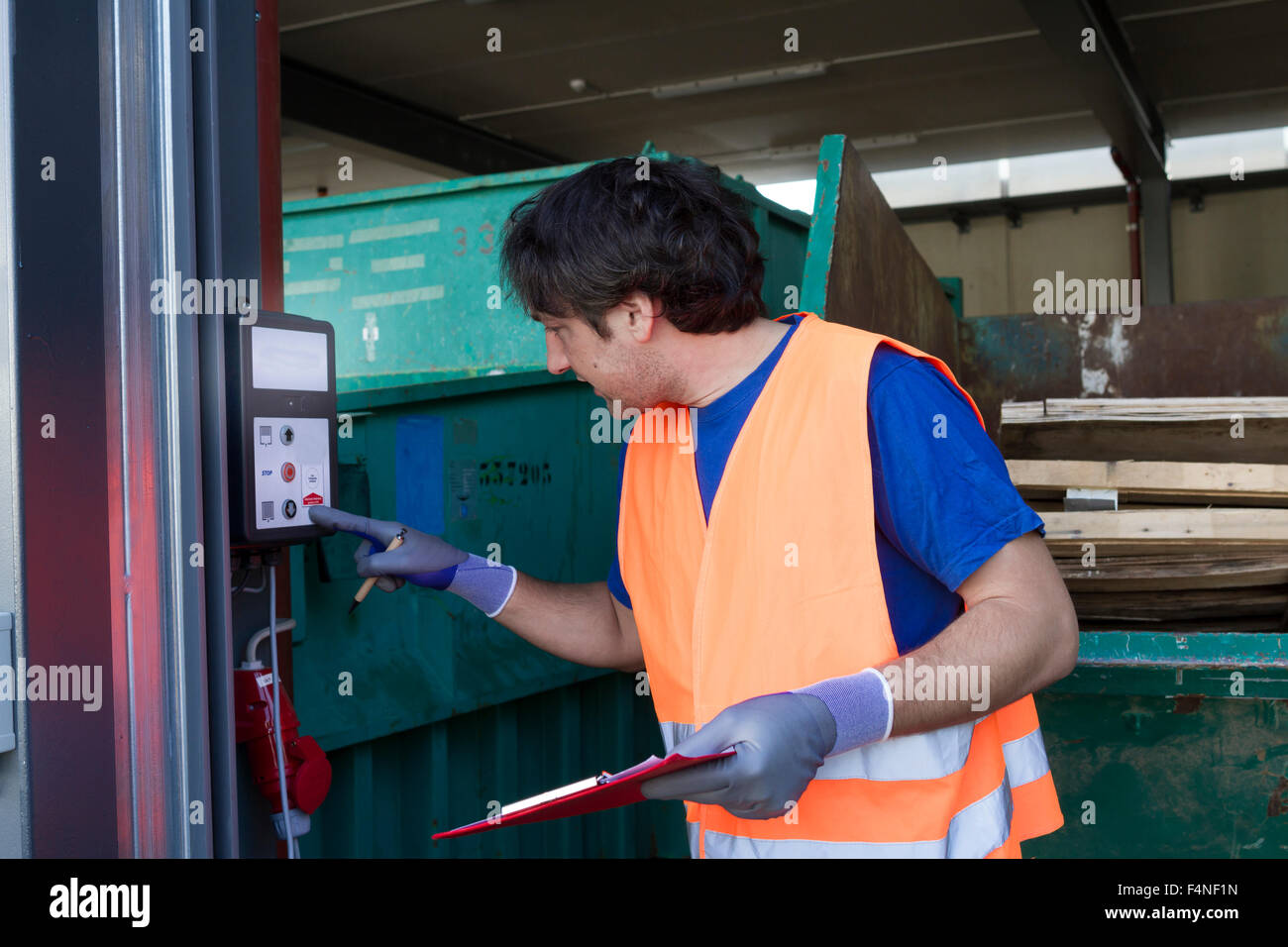 Worker at a waste container operating machine Stock Photo - Alamy