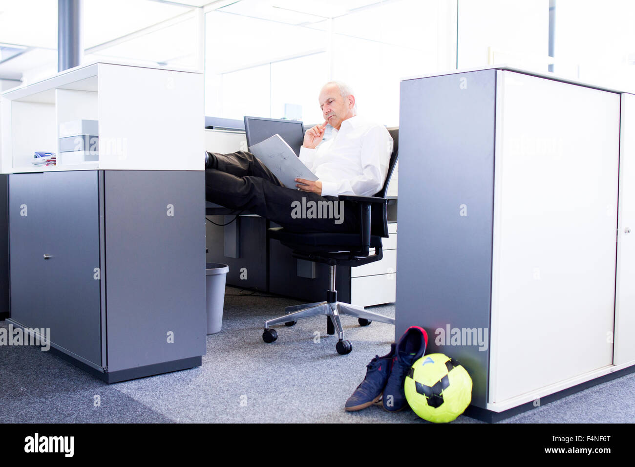 Businessman in office cubicle reading document Stock Photo - Alamy