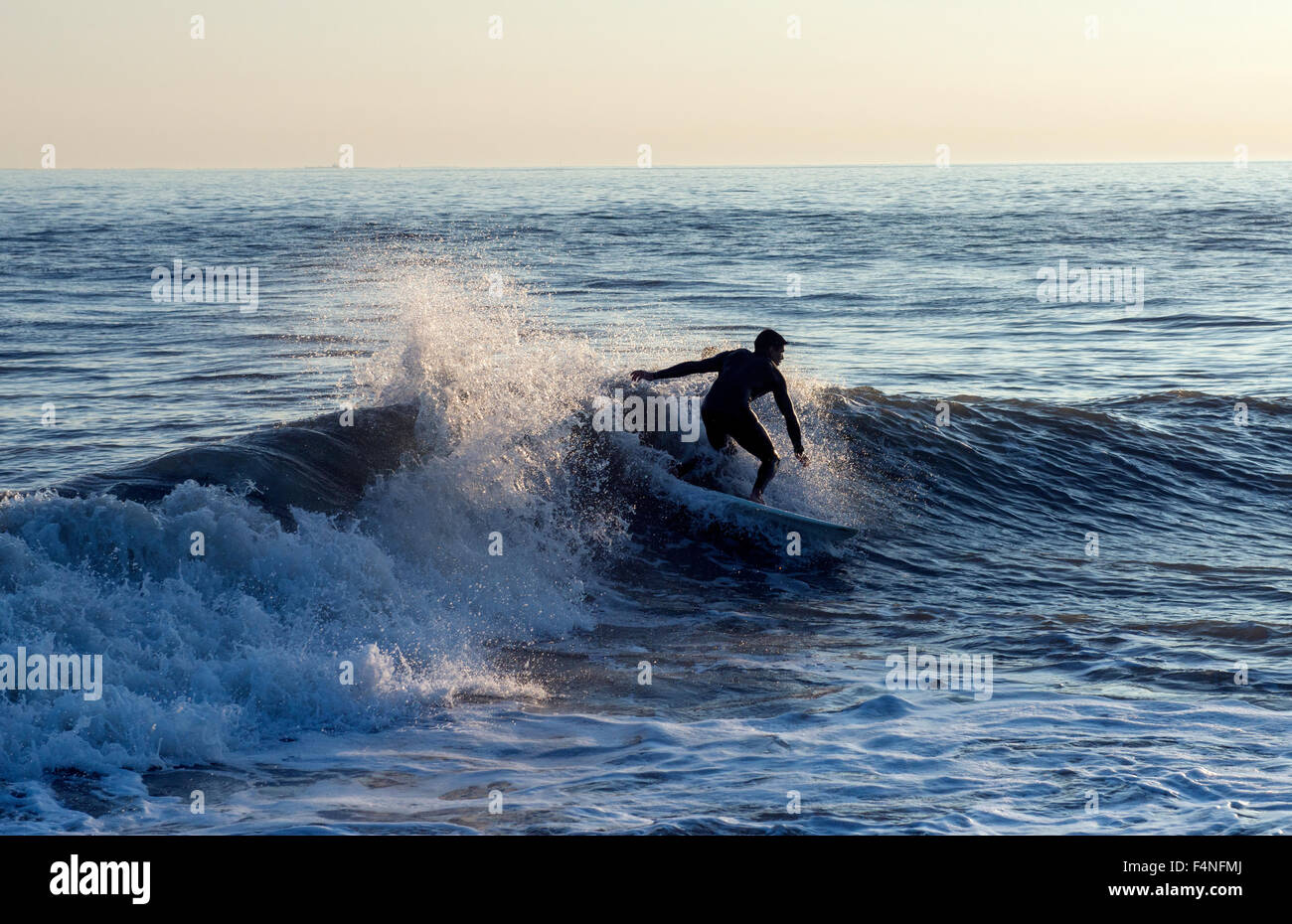 Surfer riding the waves at dusk, Cape May New Jersey USA Stock Photo ...