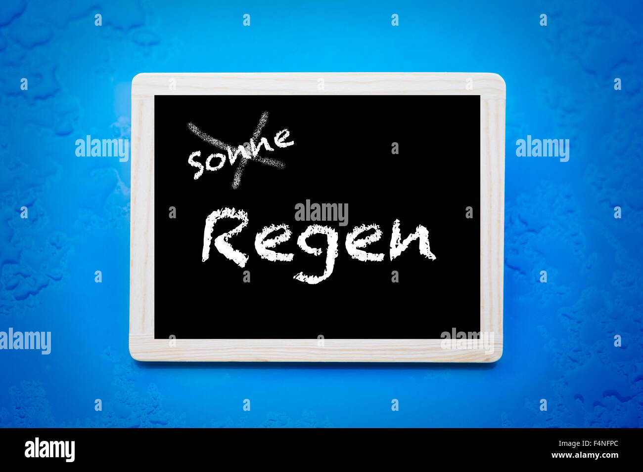 german words 'Sonne-Regen' (sun-rain) on blackboard on blue wet ...