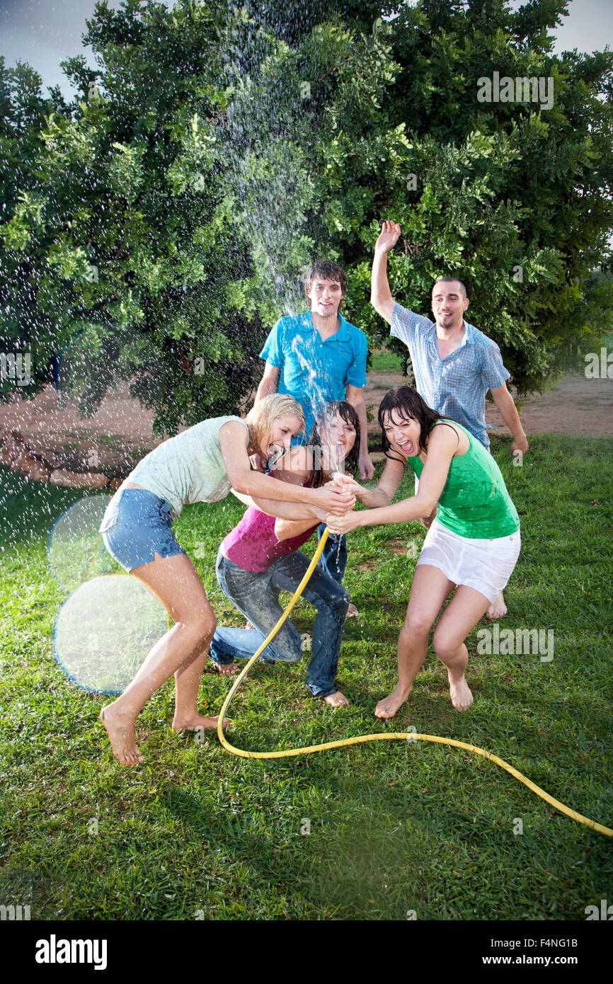 Five friends splashing with water in the garden Stock Photo - Alamy