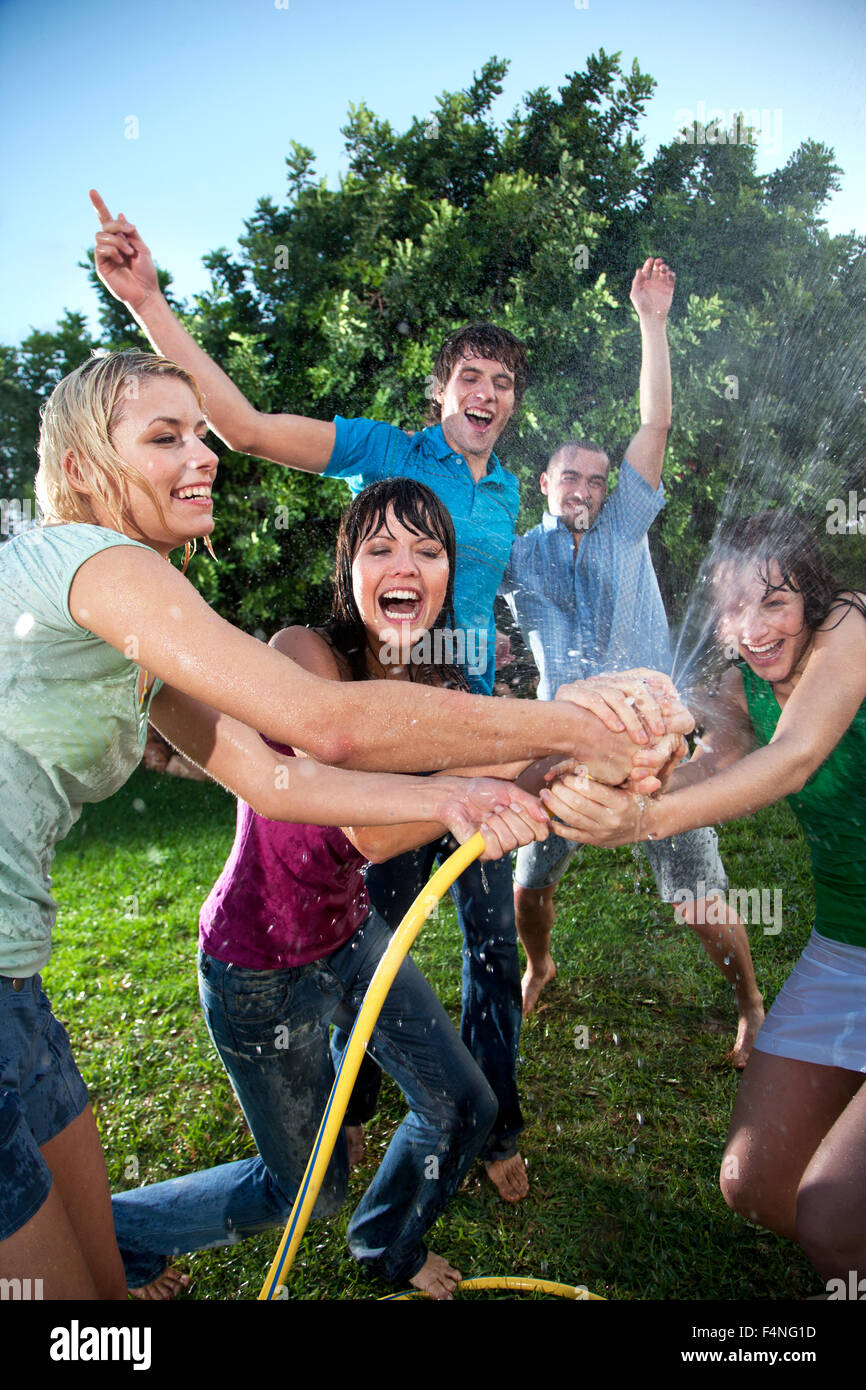 Five friends splashing with water in the garden Stock Photo - Alamy