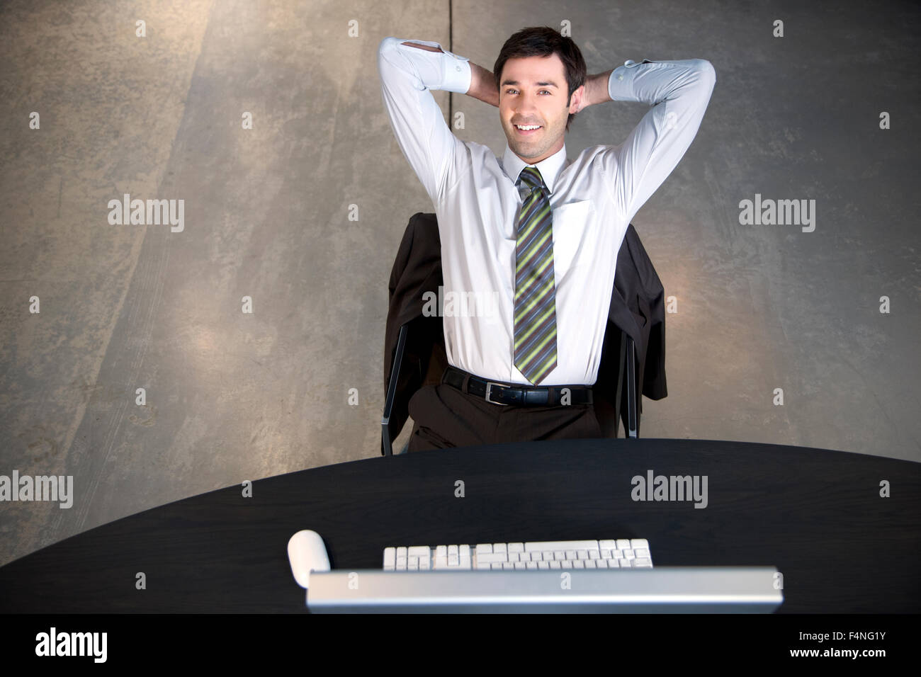 Confident businessman sitting at desk Stock Photo - Alamy