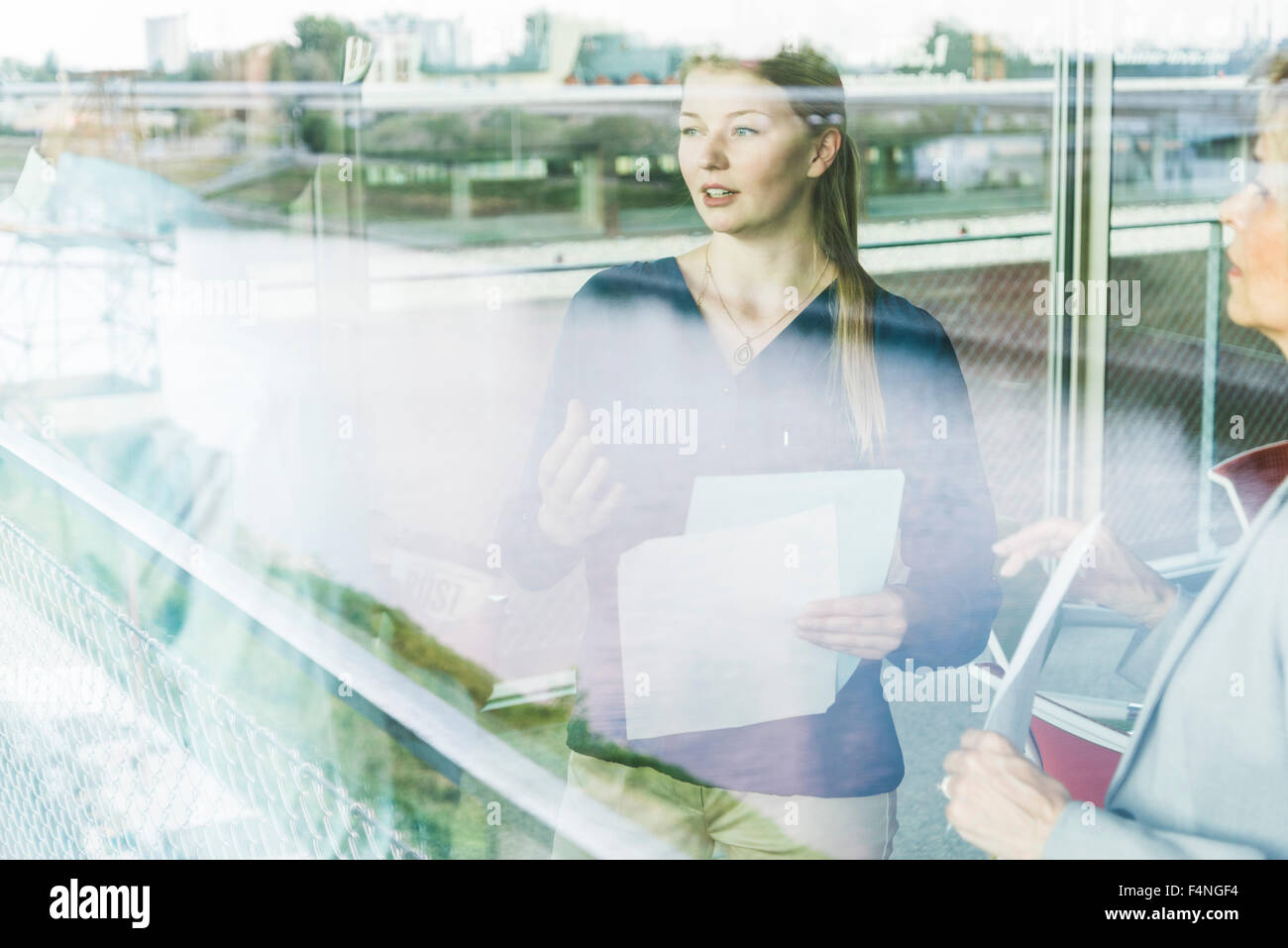 Business people with documents talking behind window pane Stock Photo ...