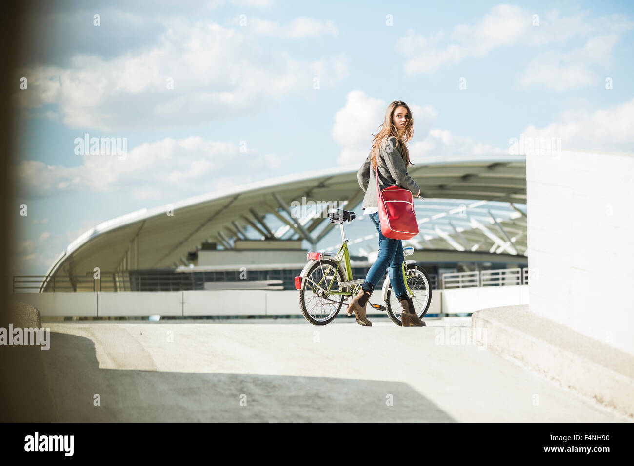 Young woman pushing bicycle Stock Photo - Alamy