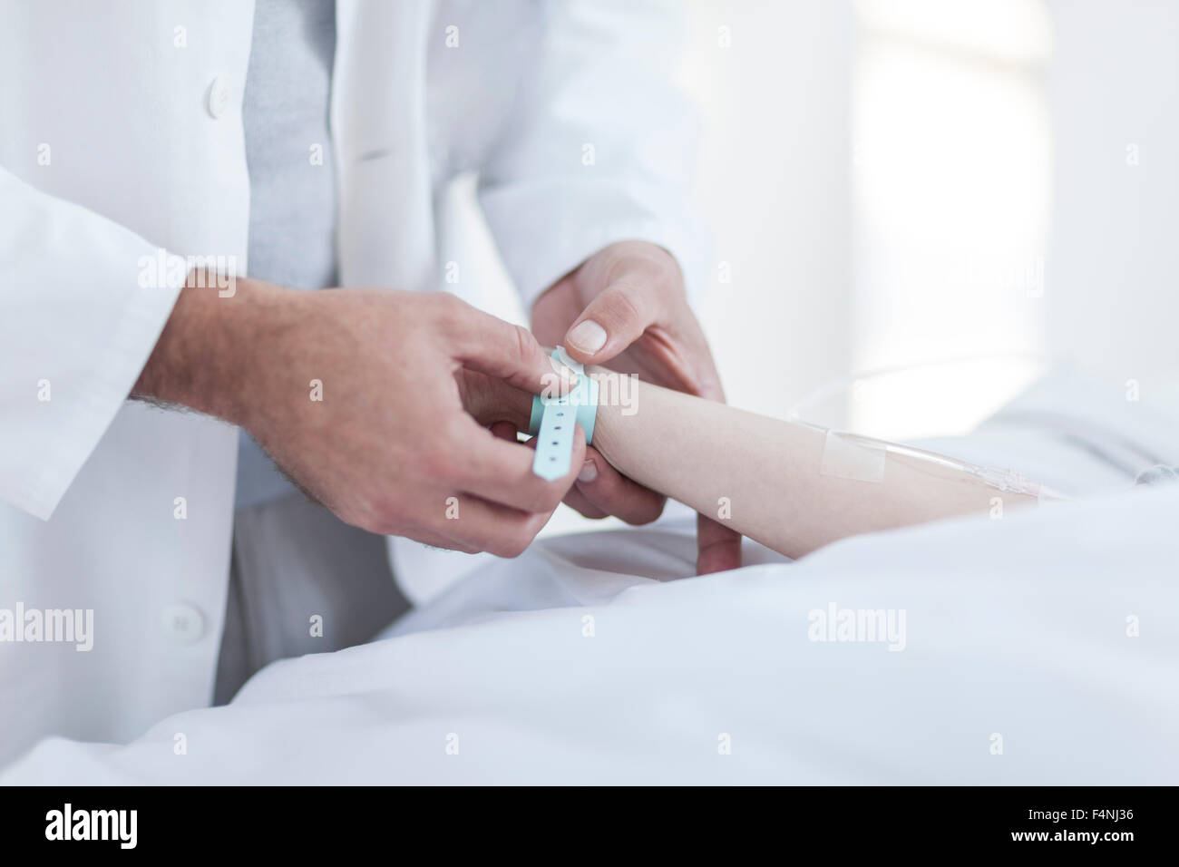 Doctor putting name tag on patient's aem Stock Photo - Alamy