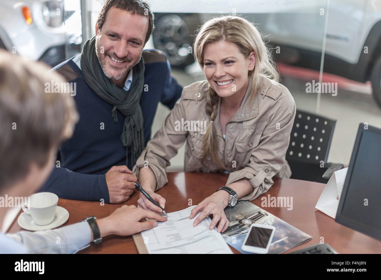 Couple signing sales contract at car dealership Stock Photo - Alamy