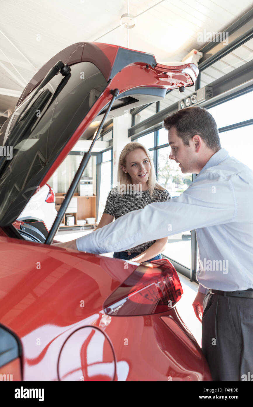 Car dealer explaining new car to young woman Stock Photo - Alamy