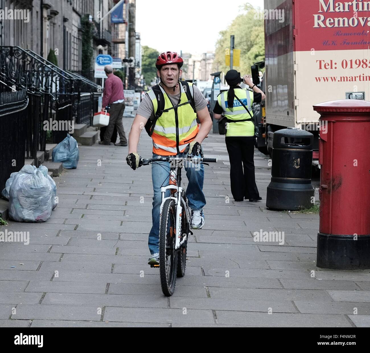 A cyclist rides his bike on the pavement in Queen Street, Edinburgh ...