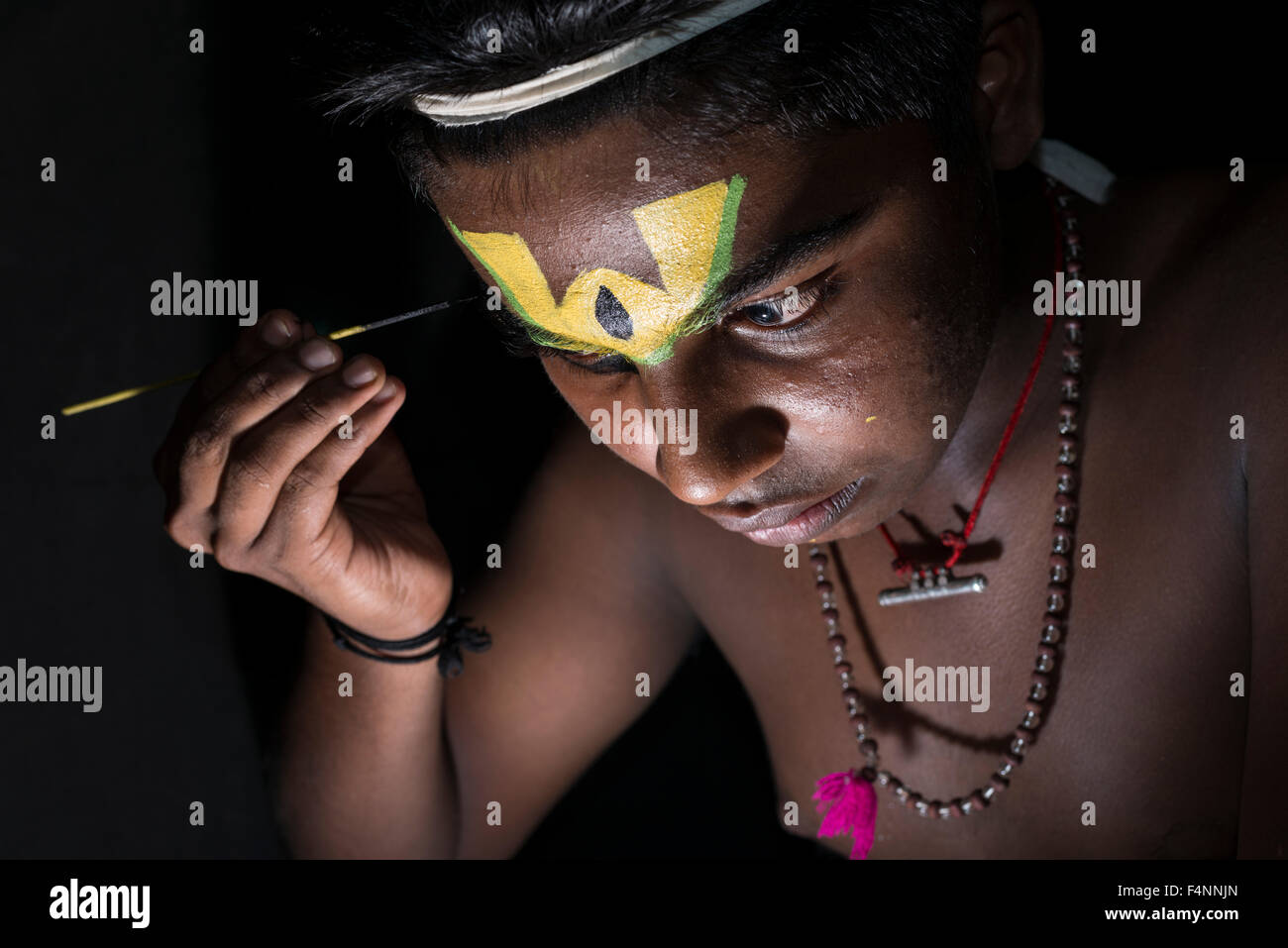 A Katakali artist is applying the make up of the character Arjun for ...