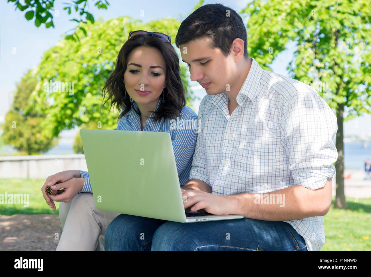 two people sitting in park with laptop computer Stock Photo - Alamy