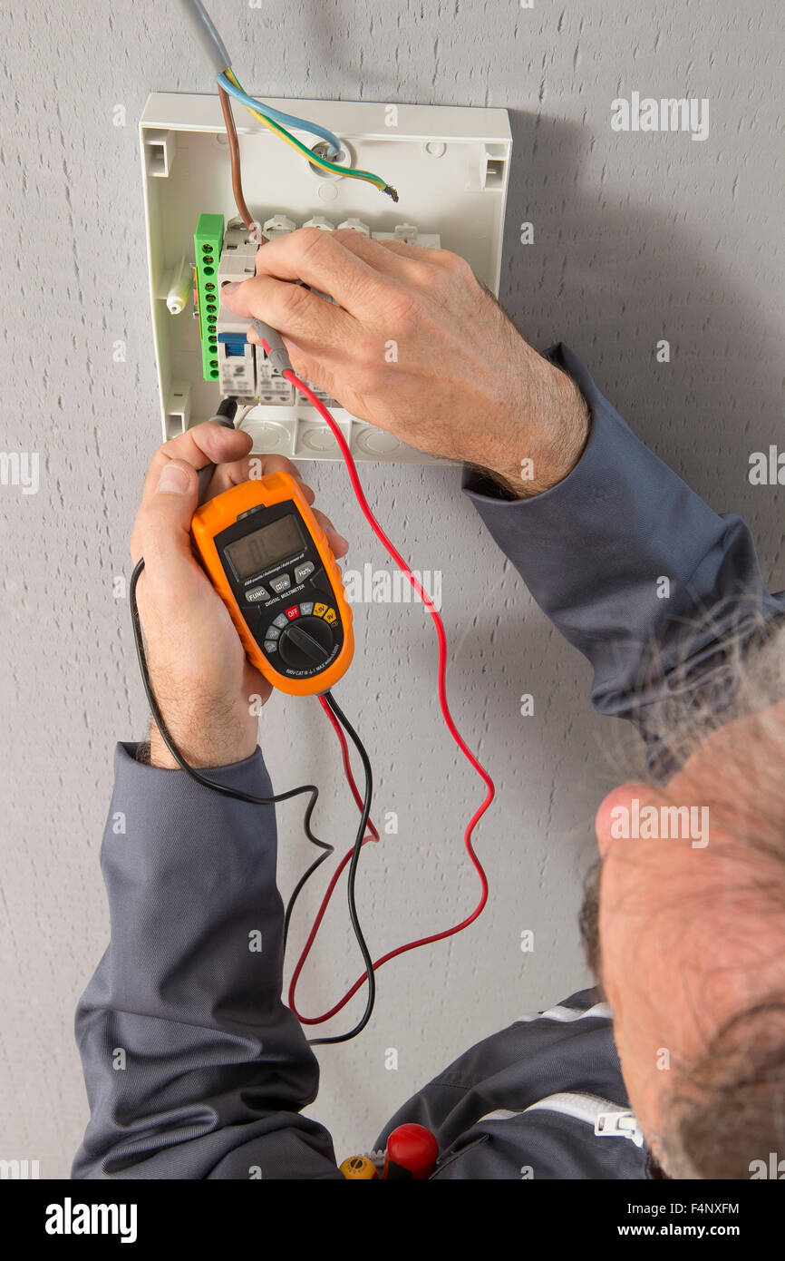 Hand of an electrician with multimeter probe at an electrical ...