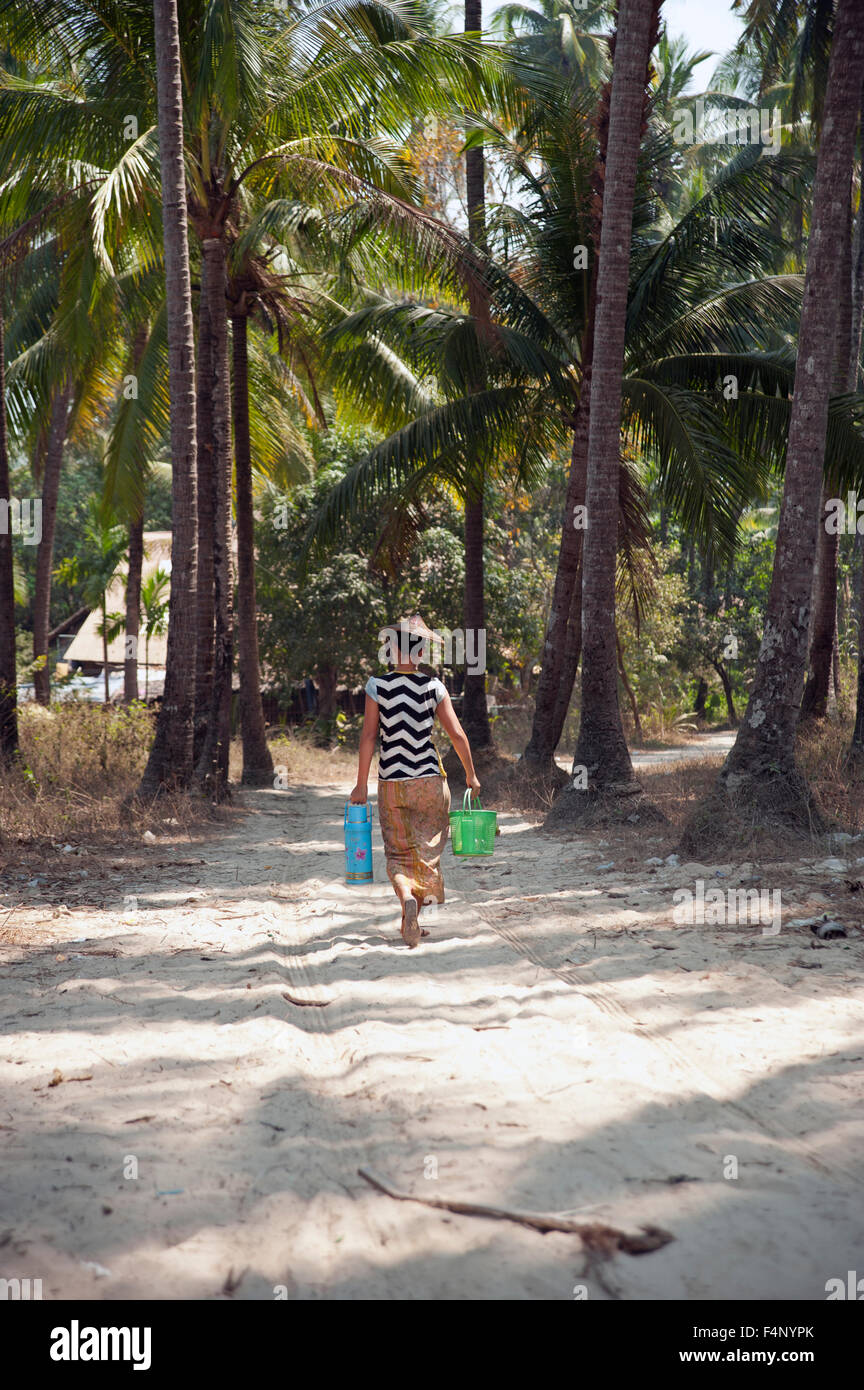Women carrying baskets of fish through the palm trees on Ngapali beach ...