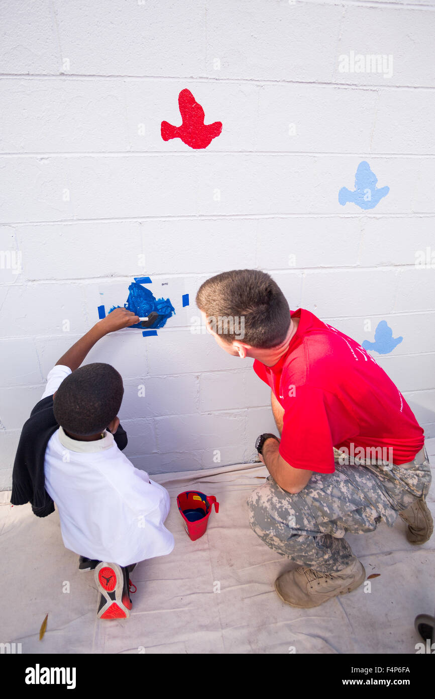 A young boy is helped by a Citadel Military college cadet to paint a ...