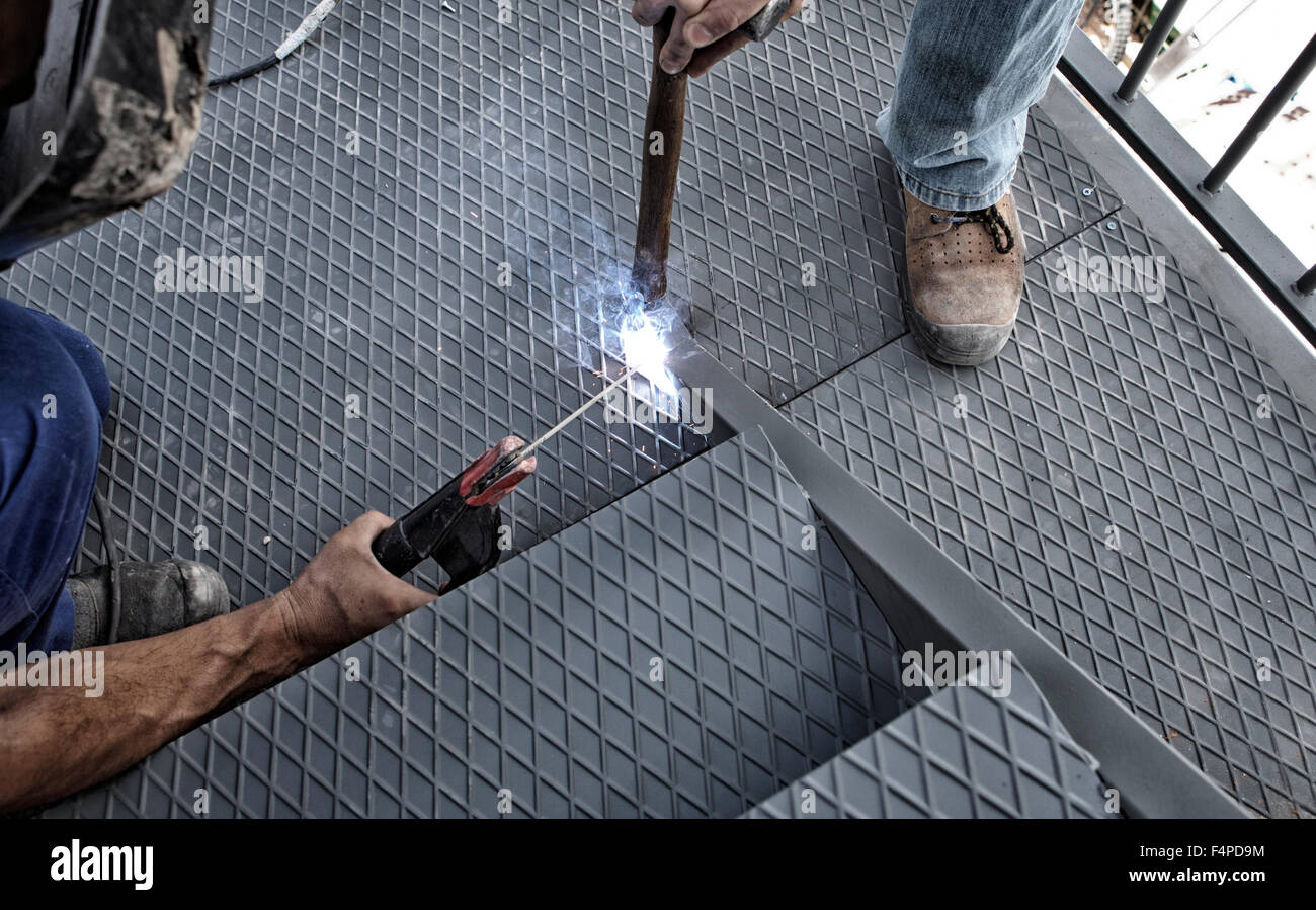 Two men working over iron platform with arc welding Stock Photo - Alamy