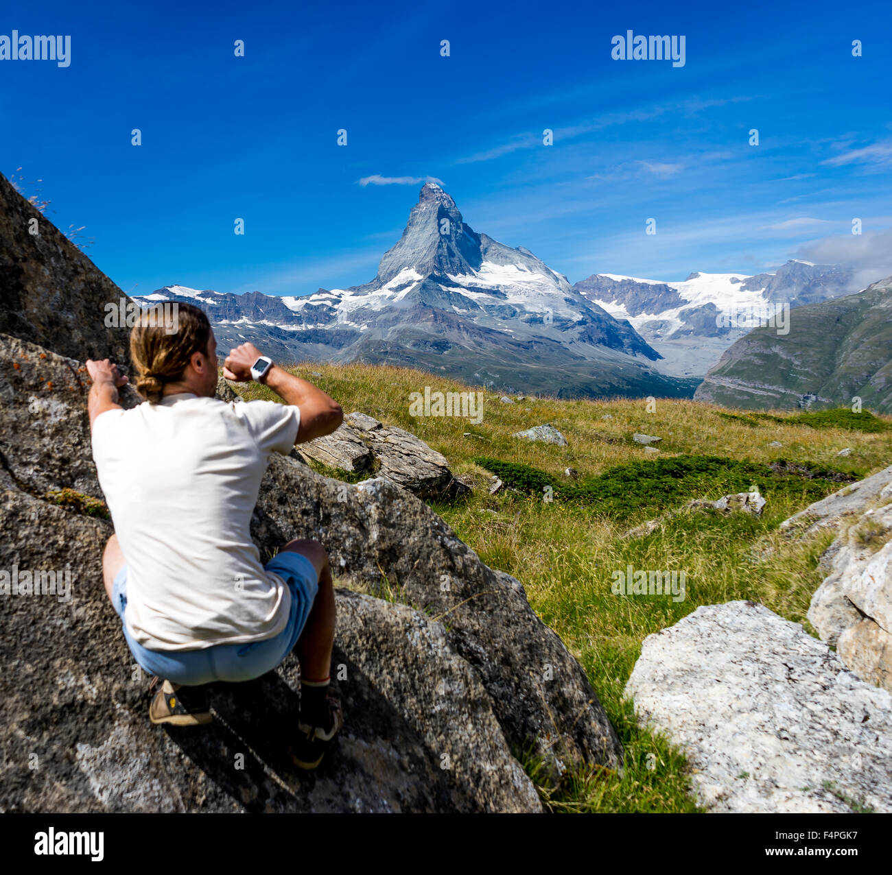 Rugged climber checks his smartwatch while climbing a boulder under ...