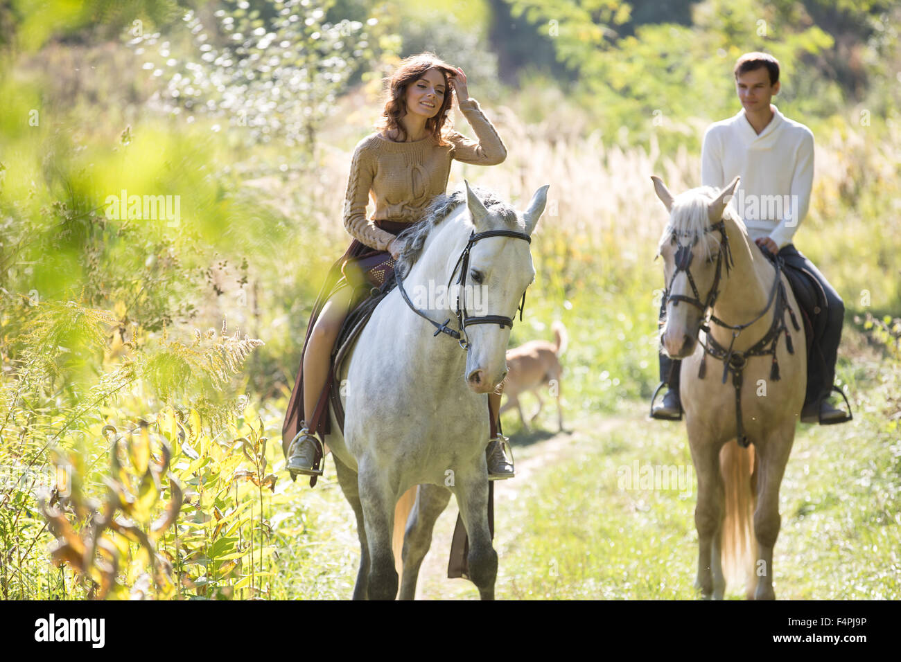 Young couple in love riding a horse walking on the background of autumn ...