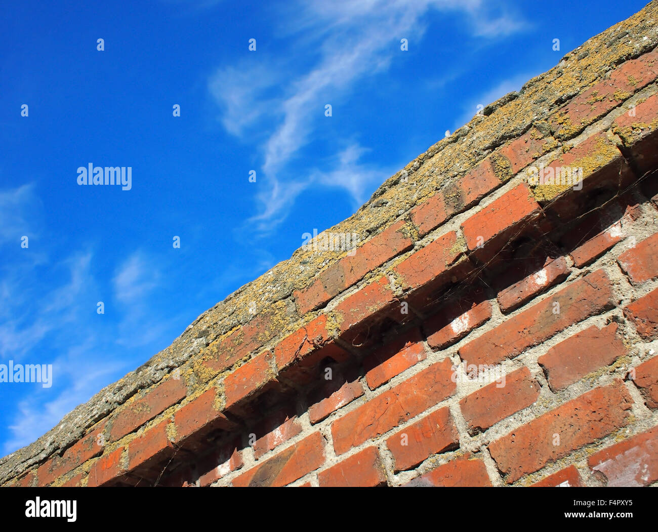 Bottom view on top of the stone wall of bricks against a bright blue ...