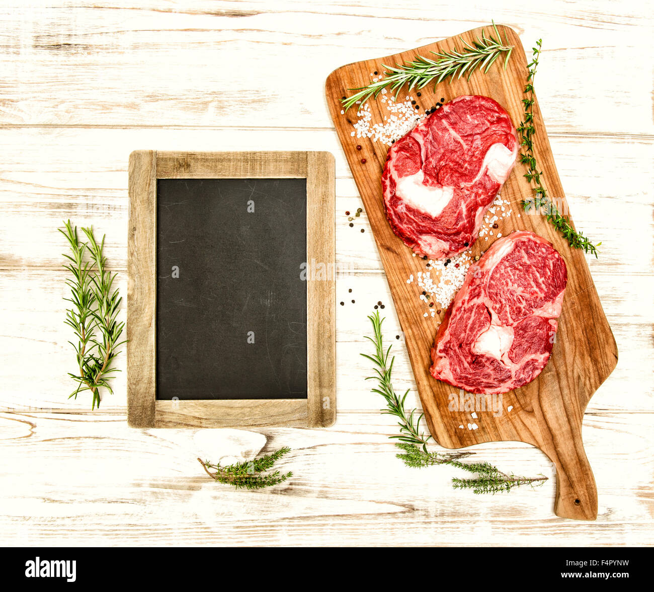 Raw fresh beef meat with herbs, spices and blackboard on wooden desk ...