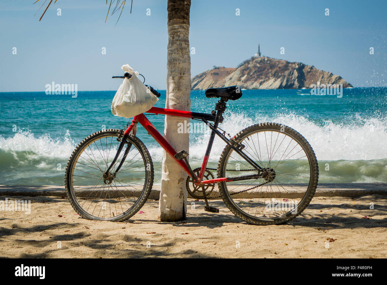 Waves splashing red bicycle leaning on palm tree in the beach Stock ...