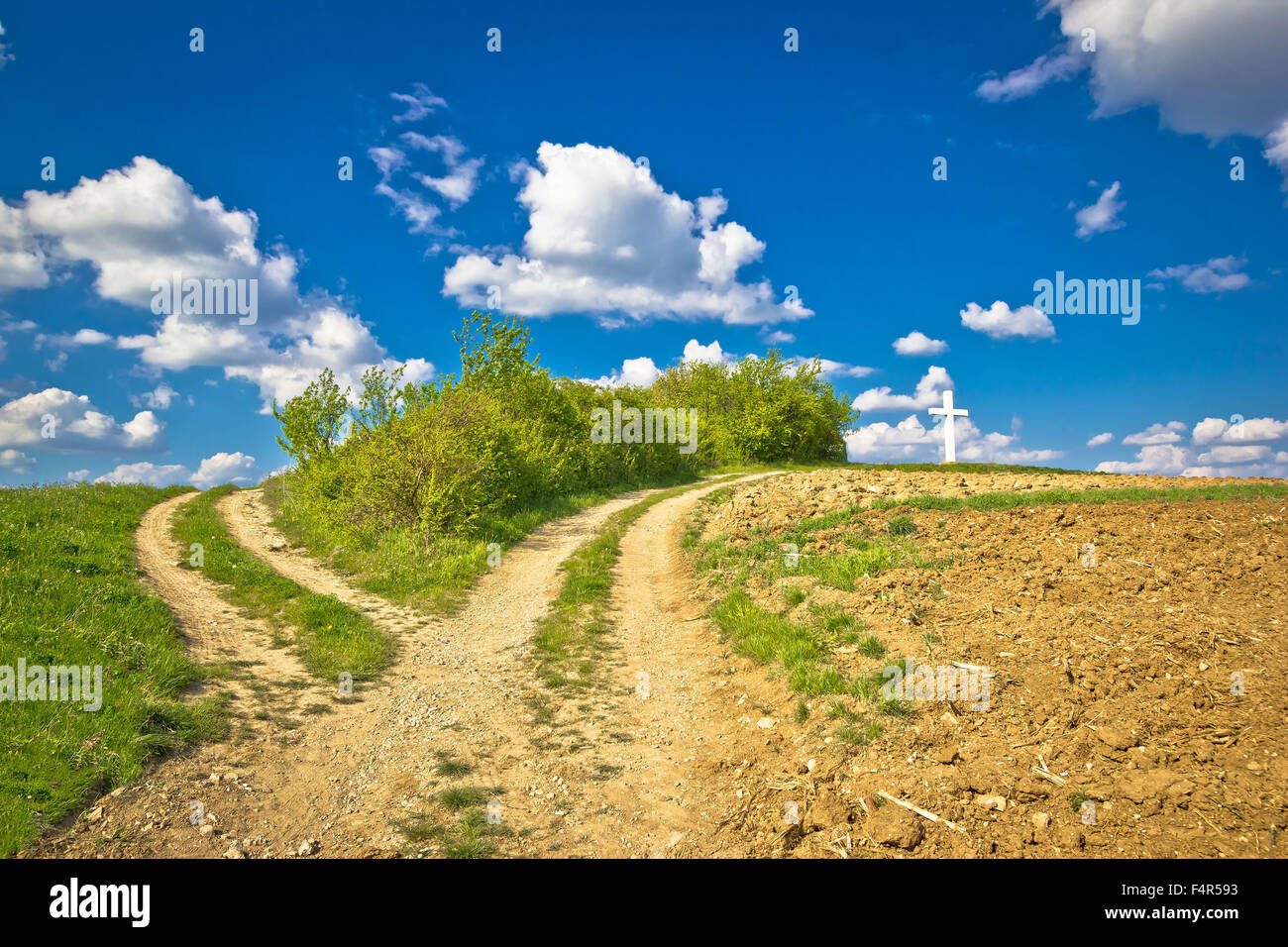 Countryside path intersection view in green nature, cross on the hill ...