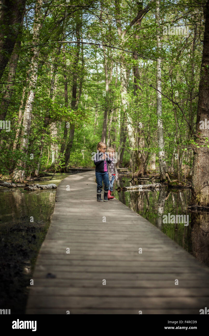 Two girls (4-5, 6-7) on walkway over swamp Stock Photo - Alamy