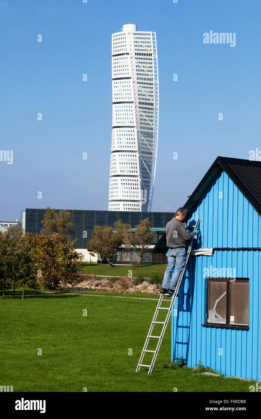 Sweden, Skane, Malmo, Man on ladder by hut and Turning Torso tower in ...