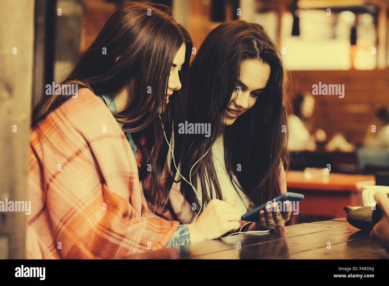 Two girl sitting listening to music Stock Photo - Alamy