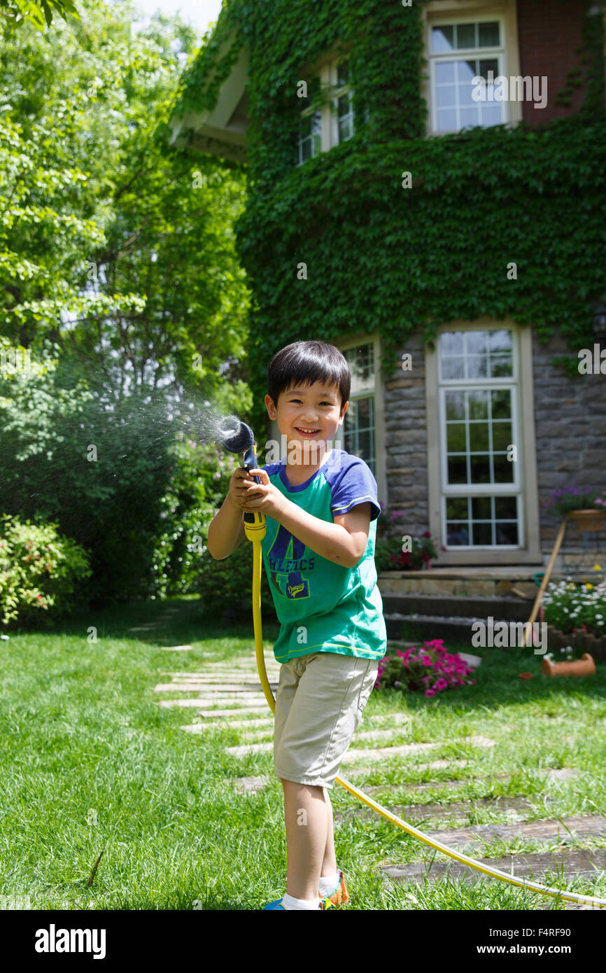 Lovely little boy in the garden watering Stock Photo - Alamy