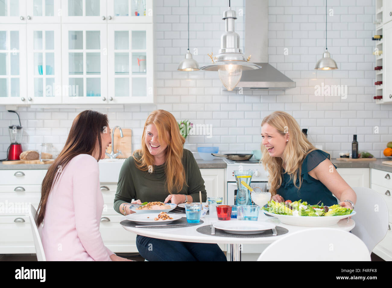 Three laughing women at kitchen table Stock Photo - Alamy