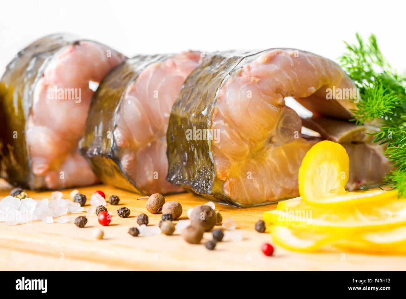 raw sliced steak of sturgeon fish with greens, lemon, different peppers ...
