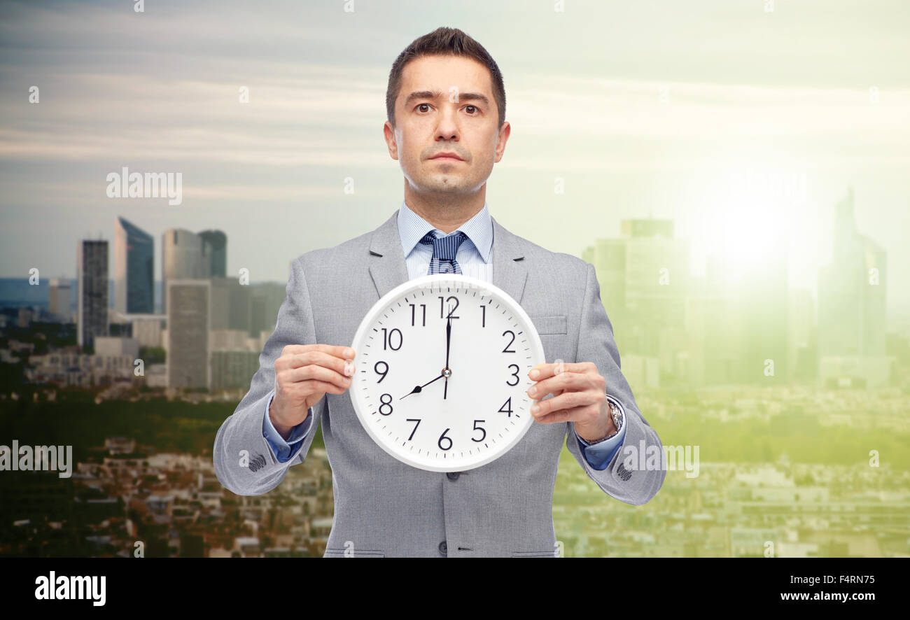 businessman in suit holding clock with 8 o'clock Stock Photo - Alamy