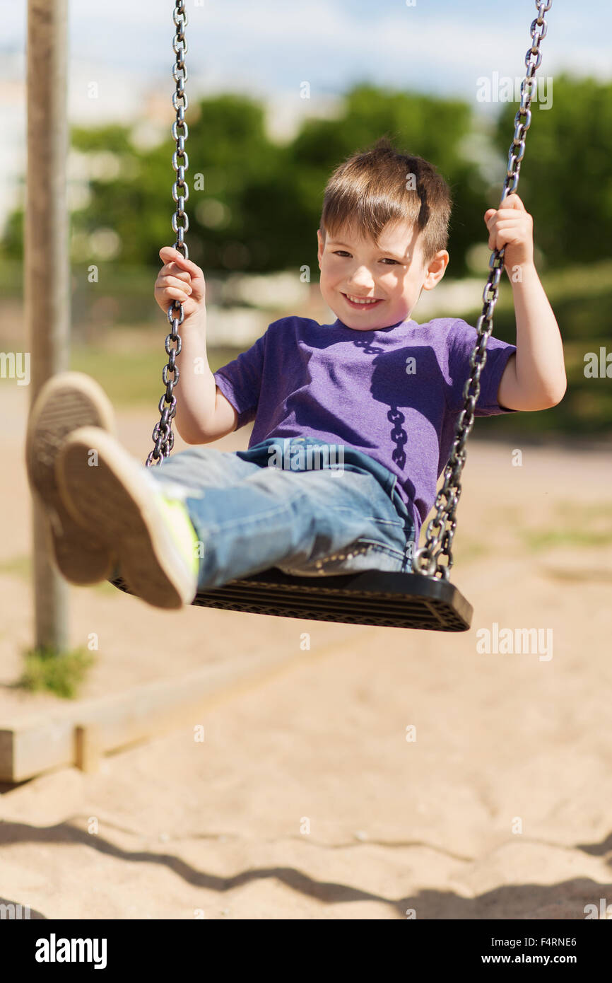 happy little boy swinging on swing at playground Stock Photo - Alamy
