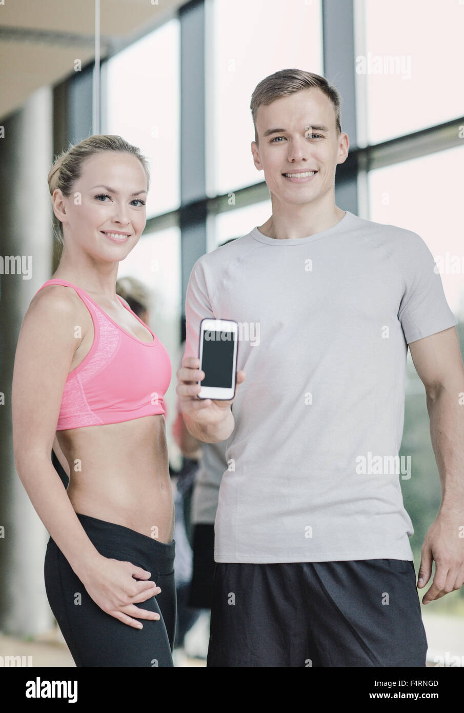 smiling young woman with personal trainer in gym Stock Photo - Alamy