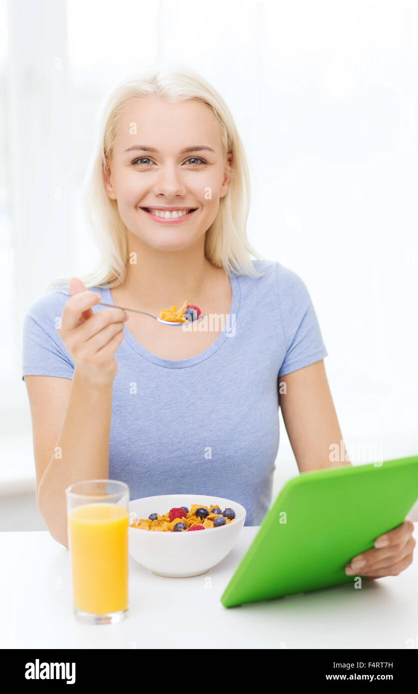 smiling woman with tablet pc eating breakfast Stock Photo - Alamy
