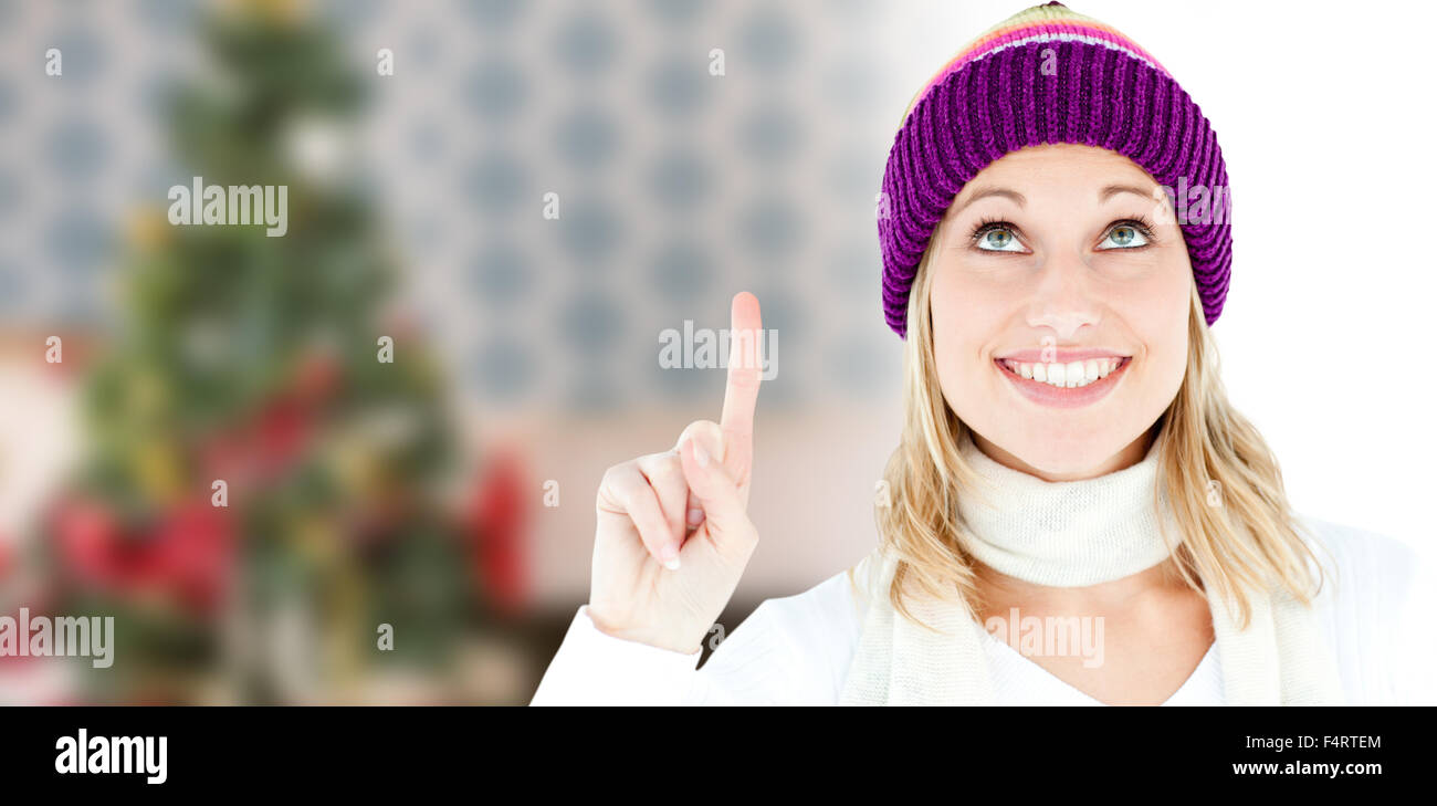 Composite image of bright woman with a colorful hat pointing upwards ...