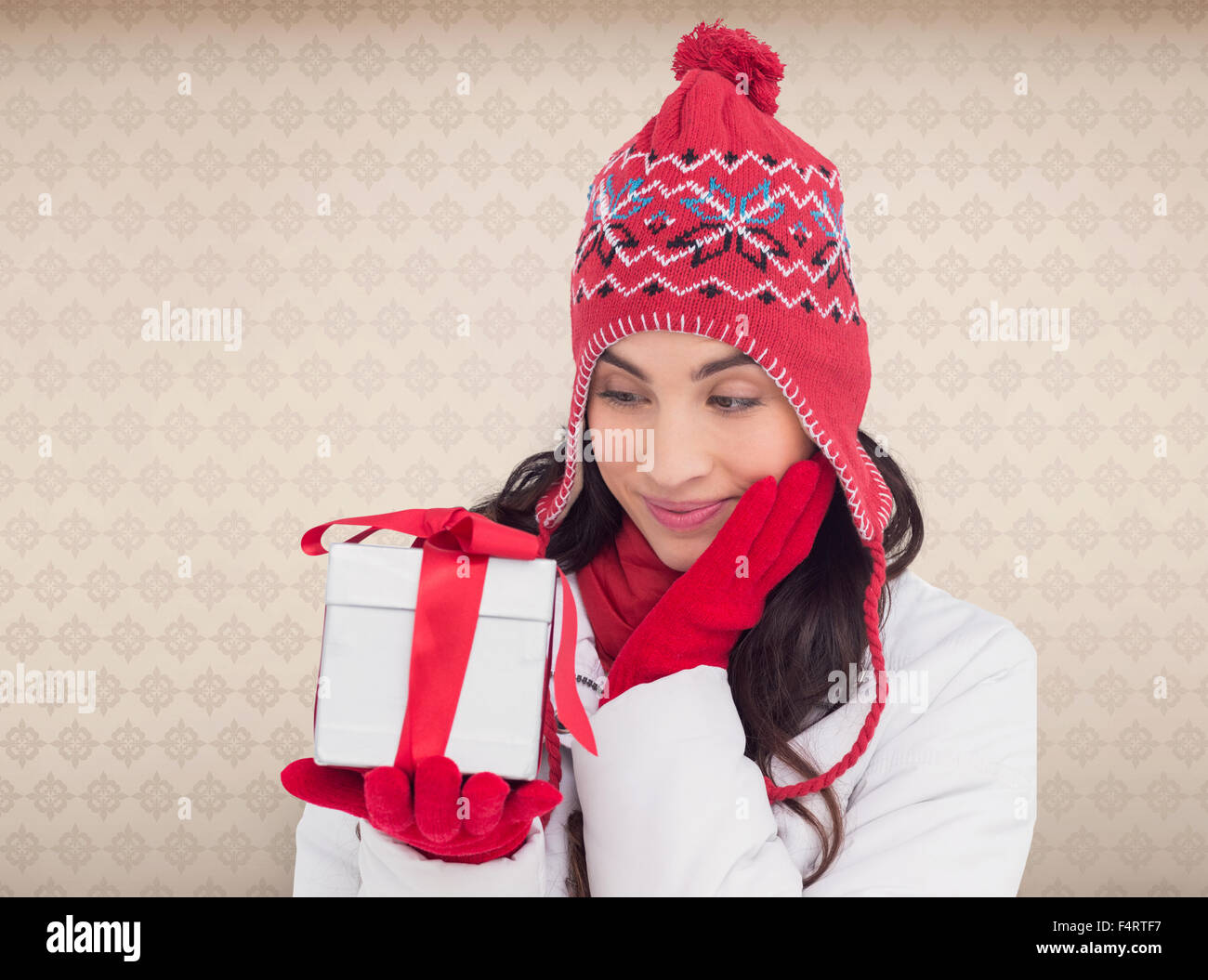 Composite image of content brunette in winter clothes holding gift ...