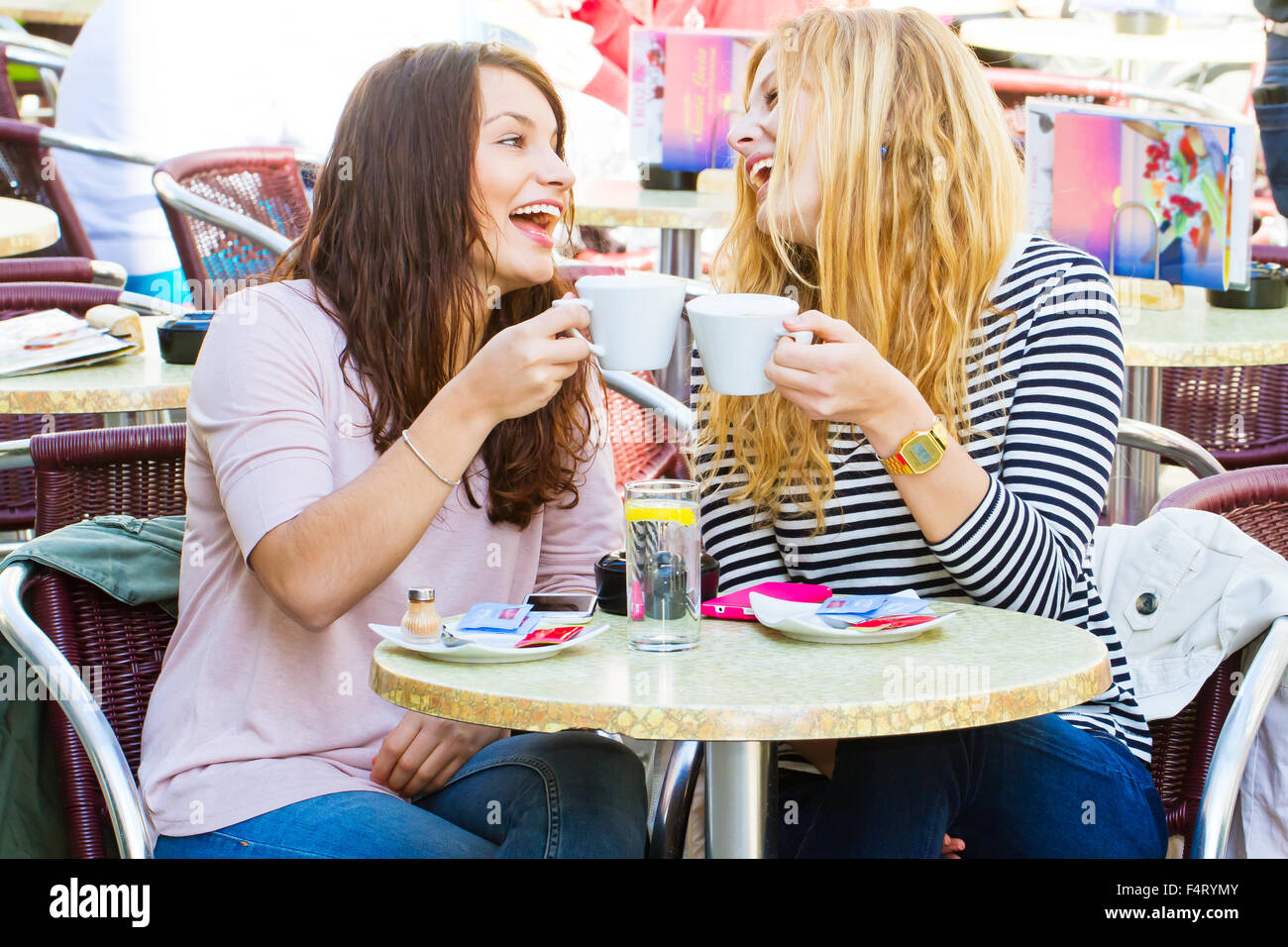 Two girls having fun in a cafe Stock Photo - Alamy