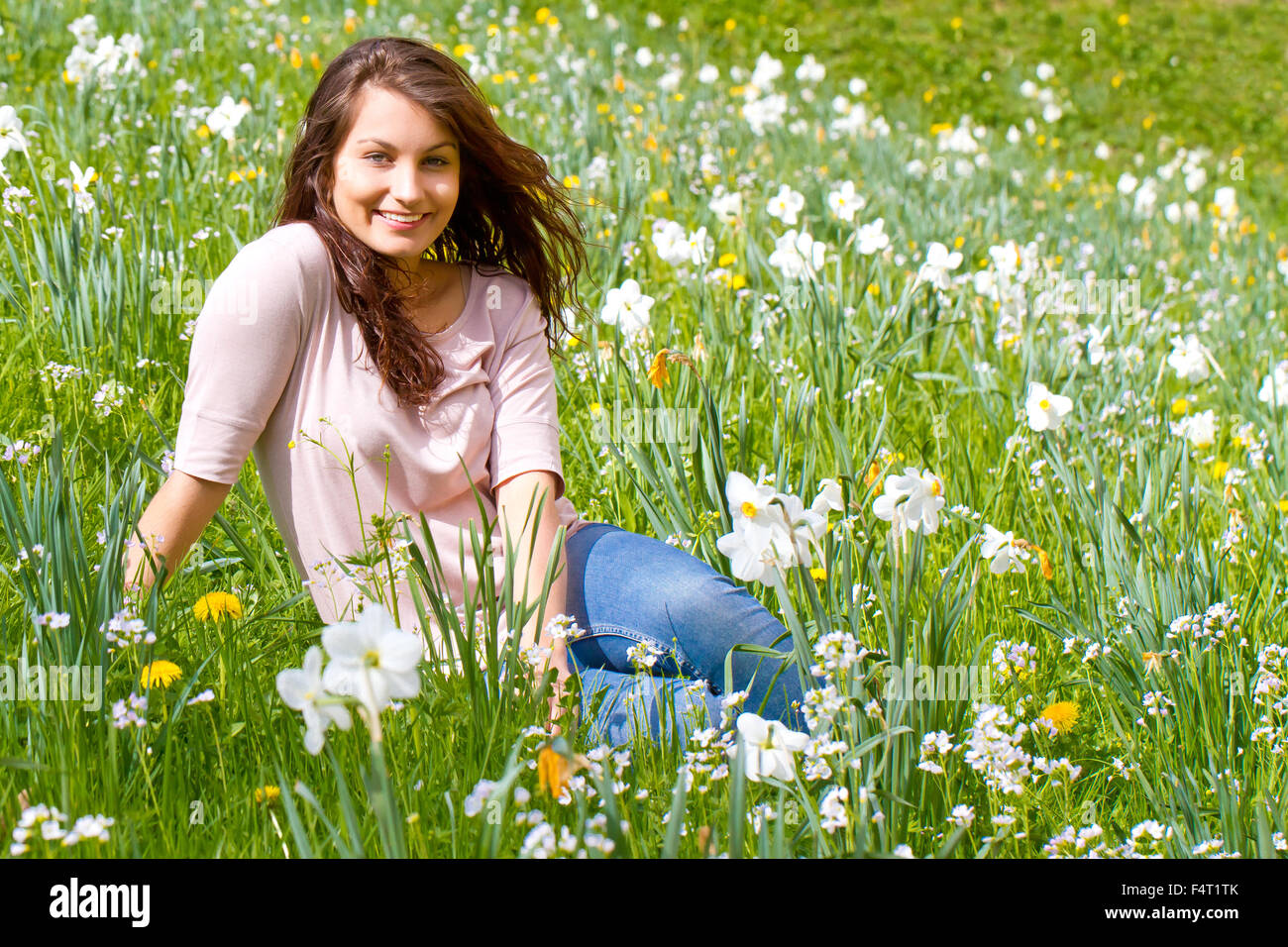 Happy girl sitting in a flower field Stock Photo - Alamy