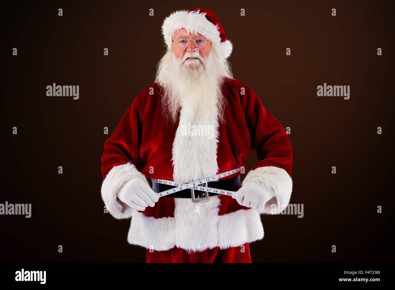 Composite image of santa claus measures his belly Stock Photo - Alamy