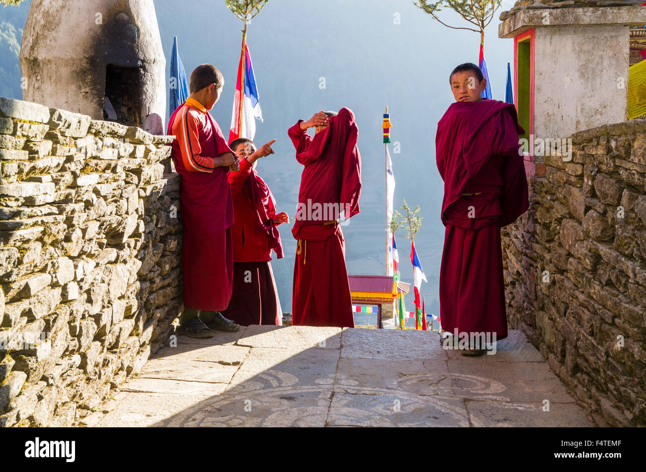 Young monks wearing red cloths standing in an alleyway Stock Photo - Alamy