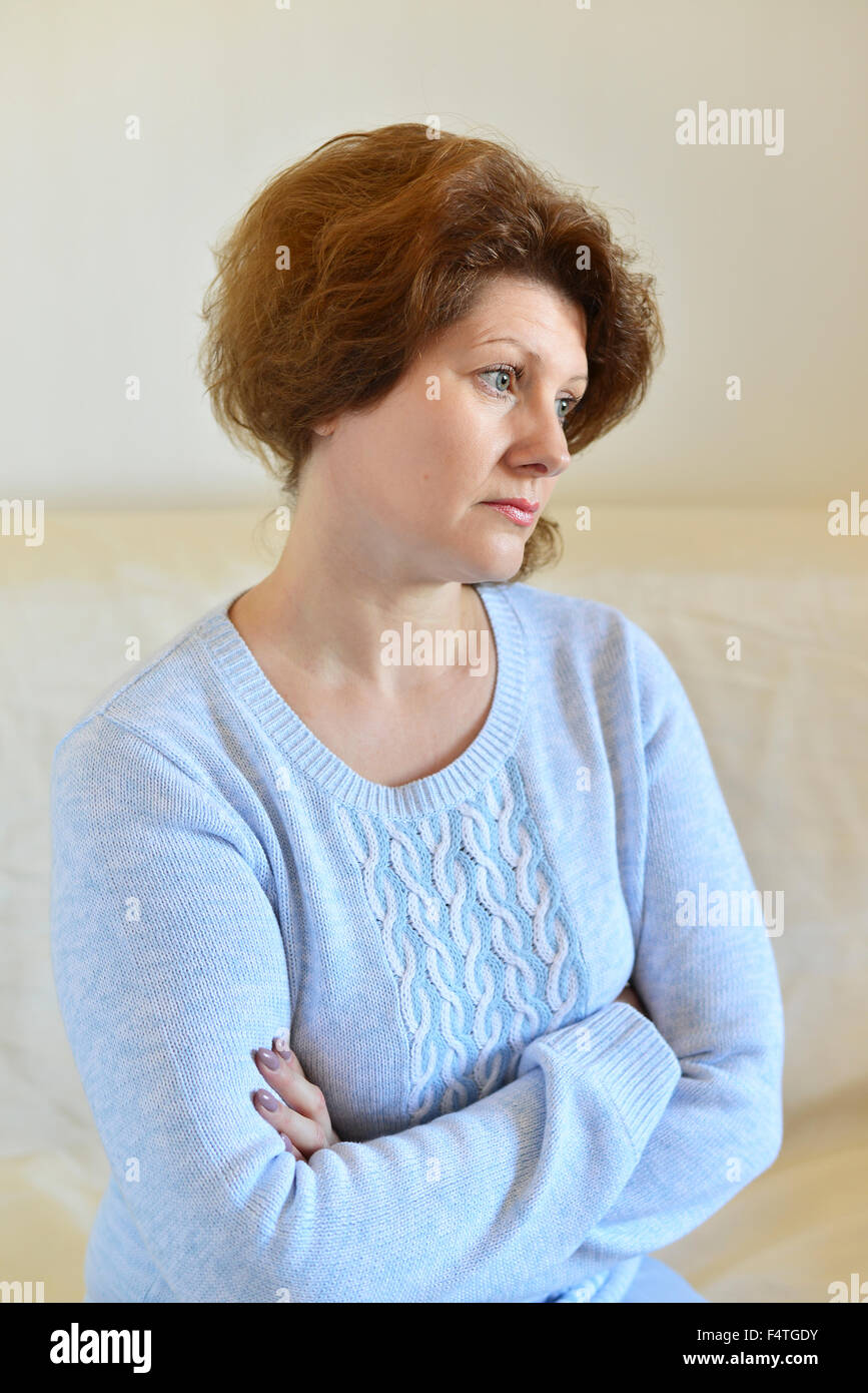 Sad woman looking away at home in living room Stock Photo - Alamy