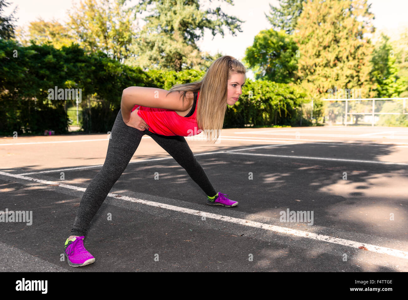 A fit female runner stops to stretch in an urban park setting Stock ...