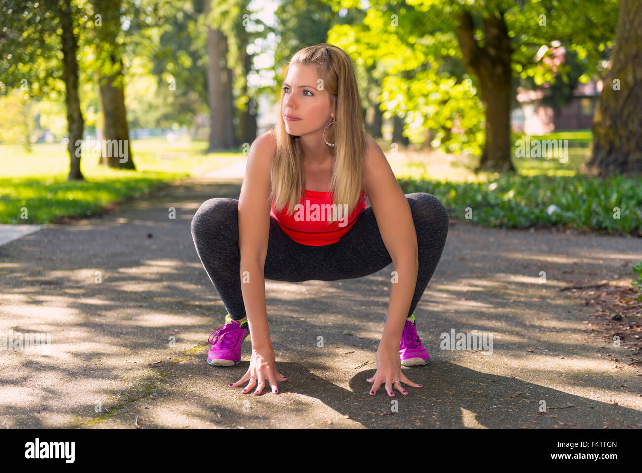 A fit female runner stops to stretch in an urban park setting Stock ...
