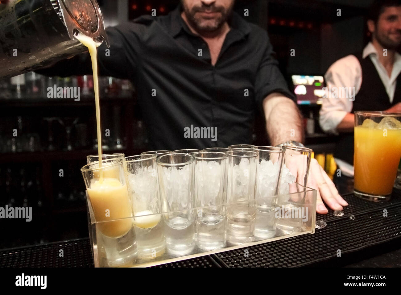 Bartender pouring cocktail shots on a tray full of shot glasses Stock ...