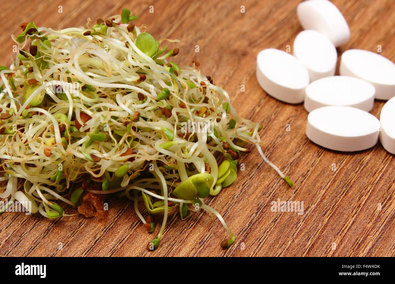 Alfalfa and radish sprouts with tablets supplements on wooden surface ...