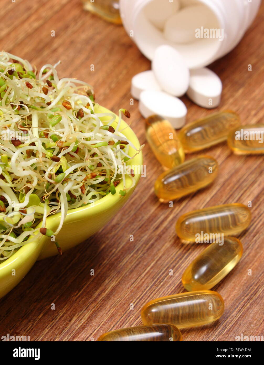 Bowl with alfalfa and radish sprouts and tablets supplements lying on ...