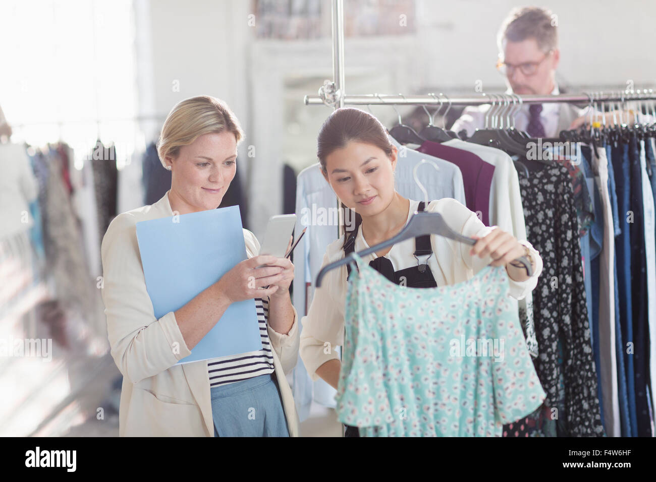 Fashion designers photographing dress with camera phone Stock Photo - Alamy