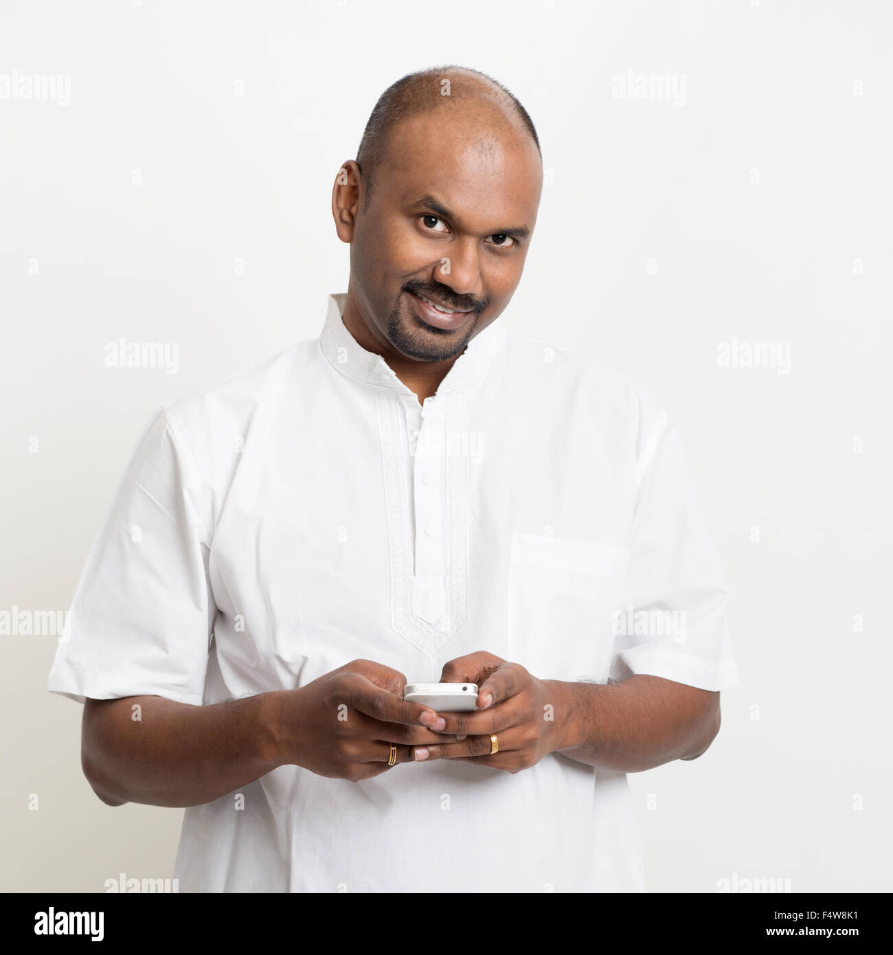 Portrait of mature casual business Indian man texting using smartphone ...